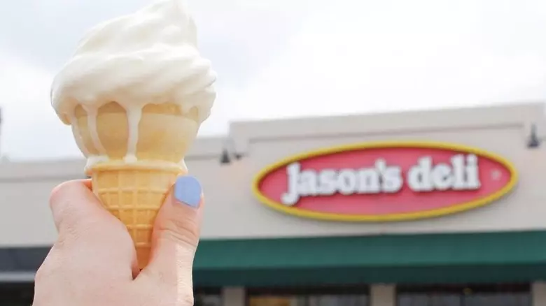 Lody w rożku trzymane wysoko przed delikatesami Jasona