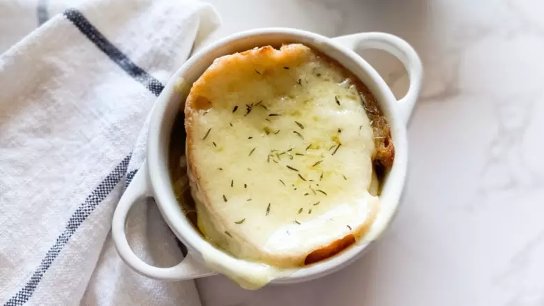 Französische Zwiebelsuppe in einem Auflaufförmchen mit einer Stoffserviette daneben