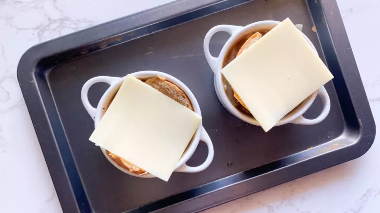 Käsescheiben auf französischem Brot auf Zwiebelsuppe in Schalen, auf einem Backblech