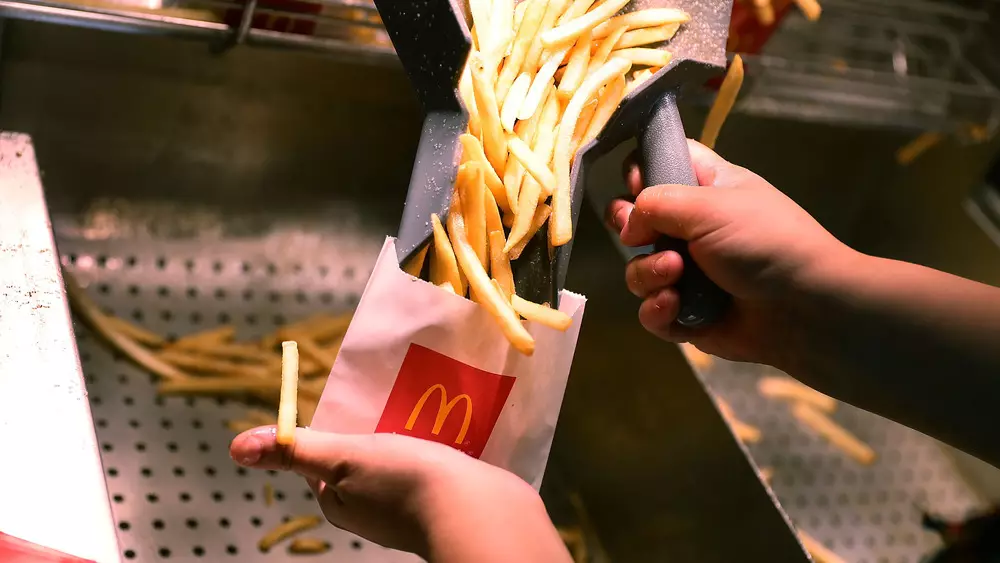 Il dipendente di McDonald's riempie un sacchetto di patatine fritte