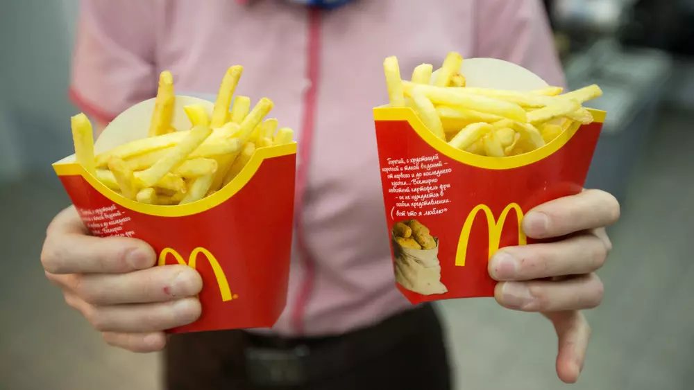 Person som holder to kartonger med McDonald's' pommes frites