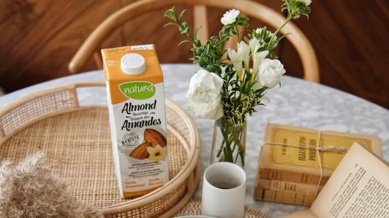 Un plateau avec du lait d'amande, des livres et un vase de fleurs