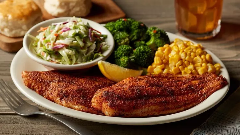 Cracker Barrel'dan bir tabakta lahana salatası, brokoli ve mısır, bisküvi ve buzlu çay ile baharatlı ızgara yayın balığı