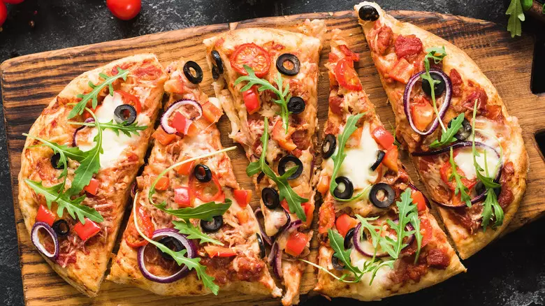 Pizza de pan plano cortada en anacos nun prato de madeira