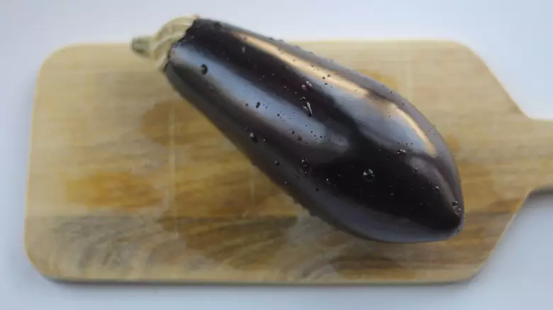 En aubergine plassert på et skjærebrett.