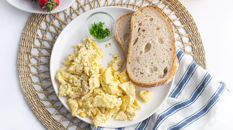 ช็อตโอเวอร์เฮดของไข่คนหนึ่งจาน ถัดจากขนมปังซาวโดว์สองสามชิ้นและกุ้ยช่ายถ้วยเล็ก