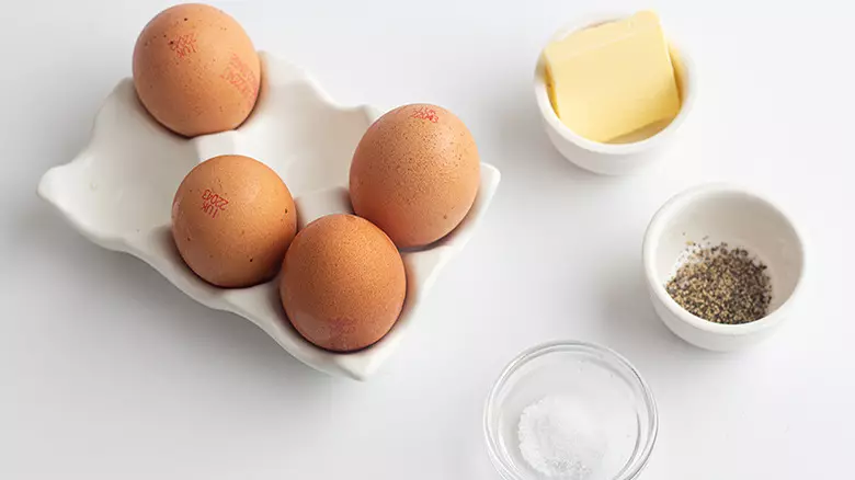 मक्खन, नमक और काली मिर्च के कंटेनरों के बगल में चार भूरे अंडे।