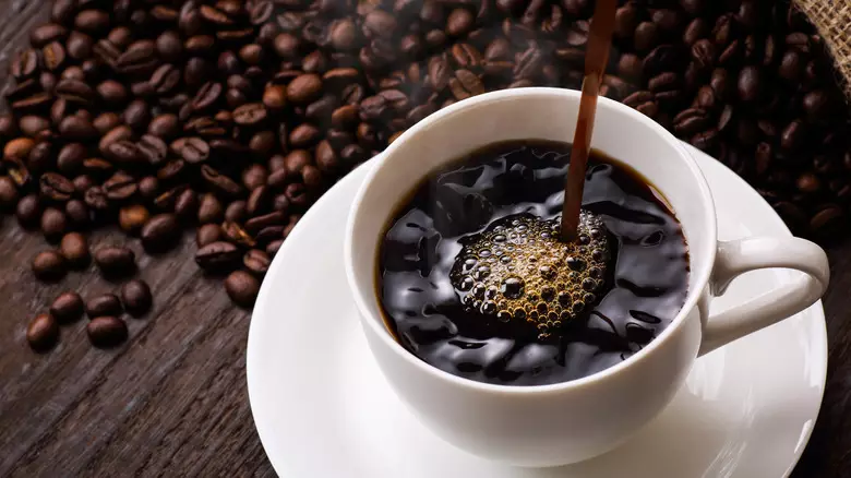 кава ў зернях за кубкам чорнай кавы