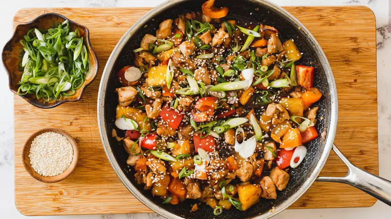 pollo teriyaki de piña a la parrilla en sartén con cebolletas y semillas de sésamo