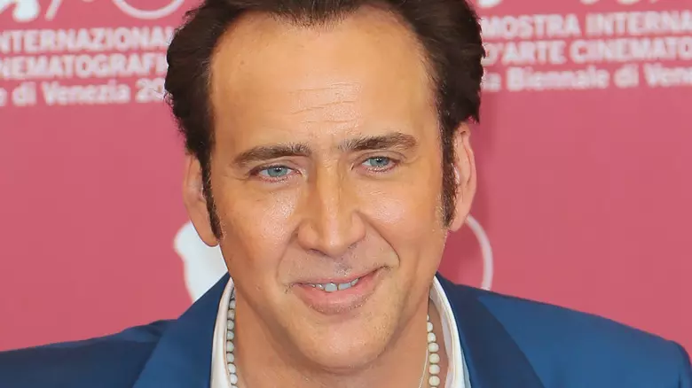 Nicolas Cage dengan latar belakang merah jambu