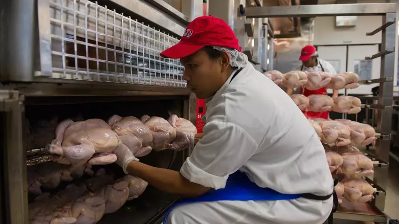 Travailleur de la charcuterie Costco au chapeau rouge avec des poulets