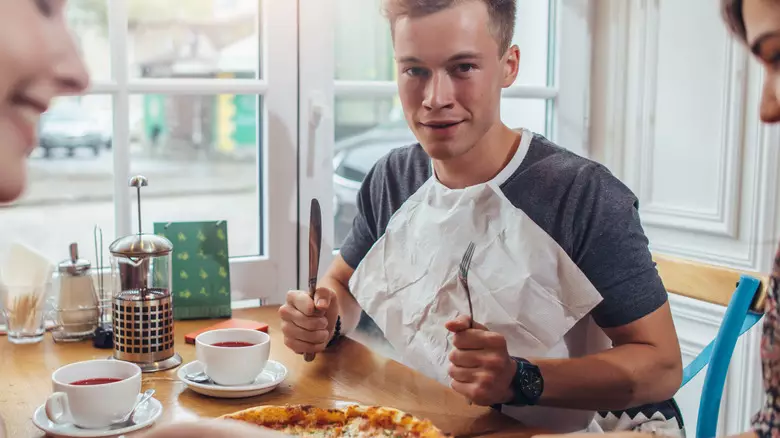 Lalaki nga adunay tinidor ug kutsilyo nga nangandam sa pagkaon sa pizza