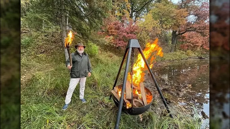 Andrew Zimmern com tocha perto do caldeirão