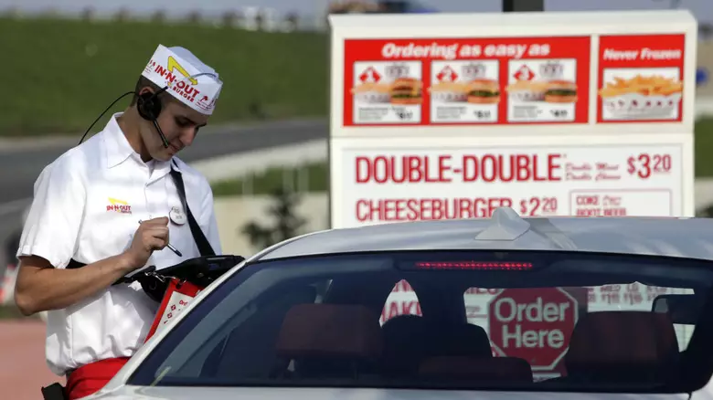 Zaměstnanec In-N-Out Burger přijímá objednávky