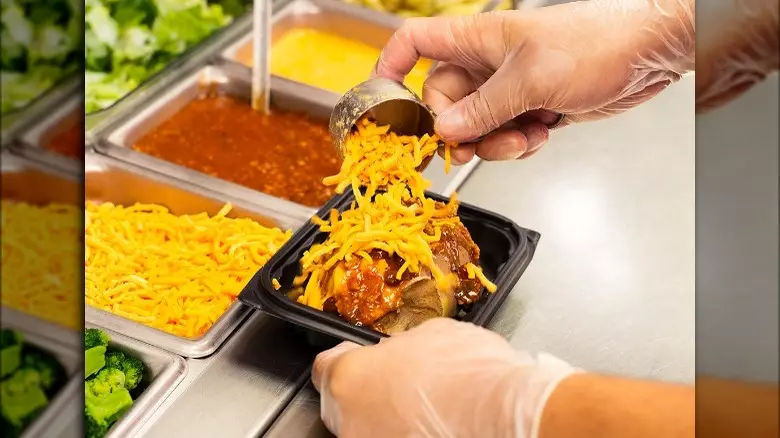 Un empleado de Wendy's aliñando una patata al horno.