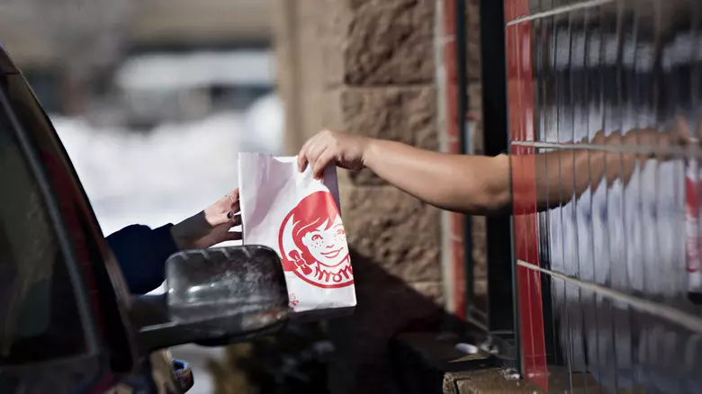 Cliente de Wendy pegando sua comida no drive thru