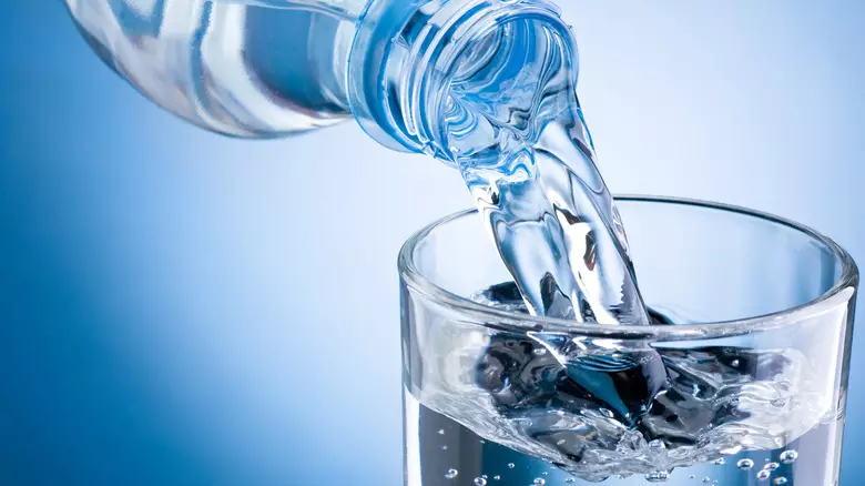 Наливание бутылки с водой в стакан