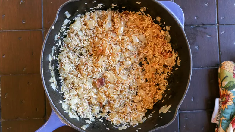 kuhanje riža in čebule v ponvi