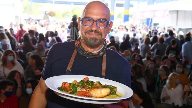 Bucătarul Michael Symon servește mâncare cu pahare albastre și cămașă