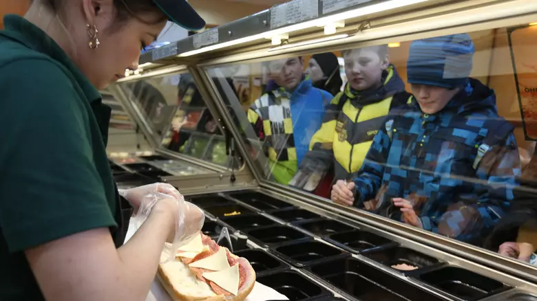 Oibrí subway ag déanamh ceapaire