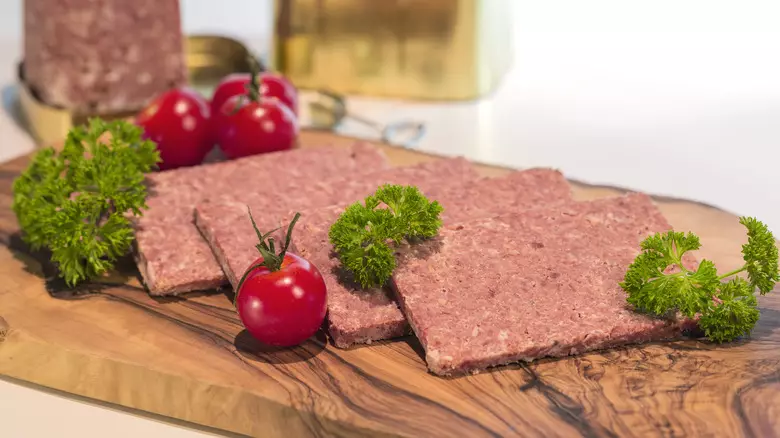 Corned Beef auf Schneidebrett mit Tomaten und Petersilie