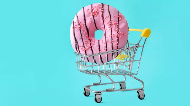 Shopping cart nga nagkupot og donut batok sa asul nga background