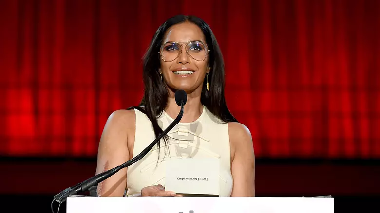 Padma Lakshmi pronáší projev v bílých šatech a brýlích