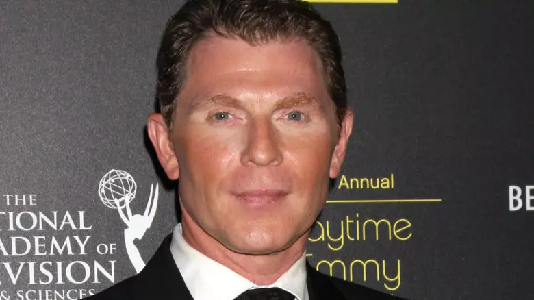 Bobby Flay က ၀တ်စုံနဲ့ လည်စည်းနဲ့ ပြုံးနေပါတယ်။