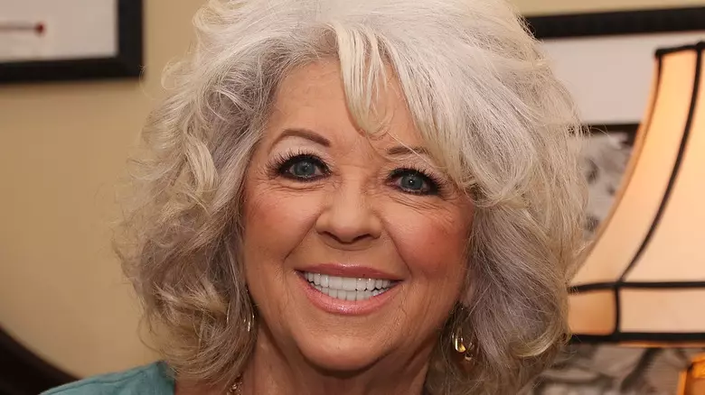 Paula Deen smiler i blågrønn topp