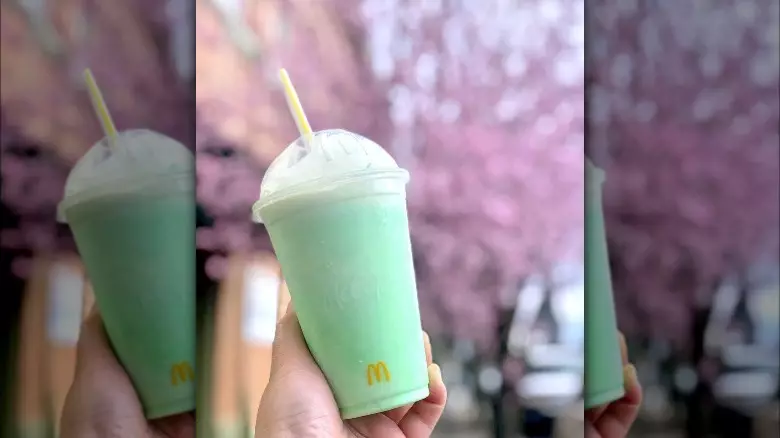 McDonald's Shamrock Shake koji se drži ispred stabla trešnjinog cvijeta