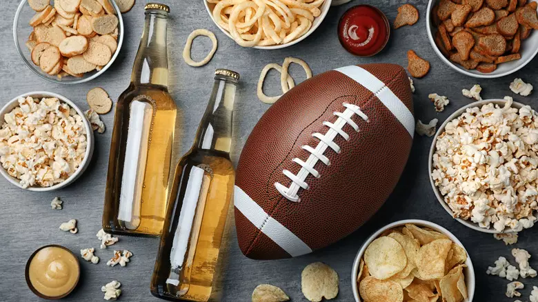 Un calcio accanto a bottiglie di birra e snack