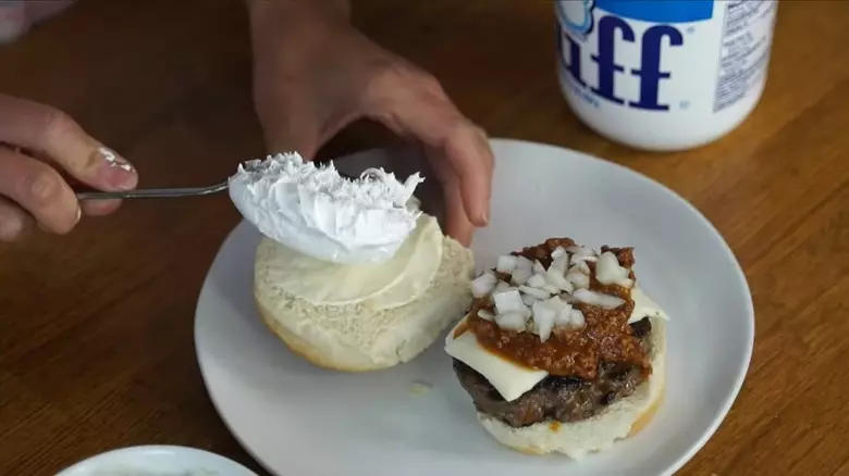 ženské ruce šíří Marshmallow Fluff na hamburger