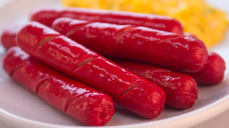 En bunke røde hotdogs på en hvid plade.
