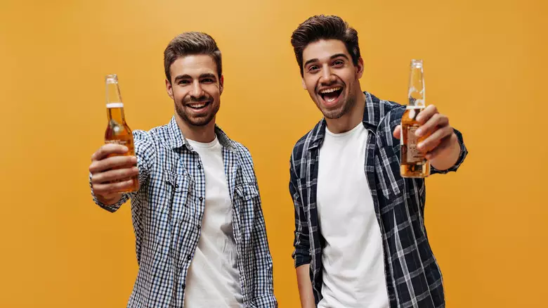 dos hombres sonriendo sosteniendo cerveza embotellada