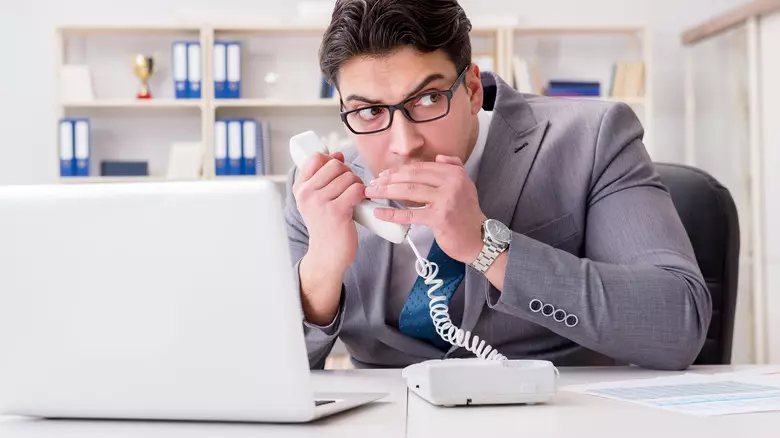 hombre de negocios filtrando información confidencial por teléfono