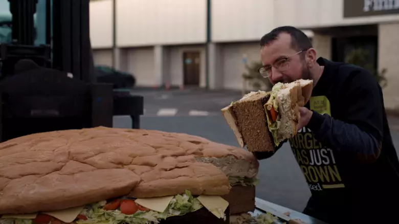 Mann som spiser massiv vegansk burger