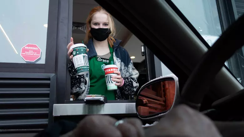 Starbucks-barista deler drinker ut av drive-thru-vinduet