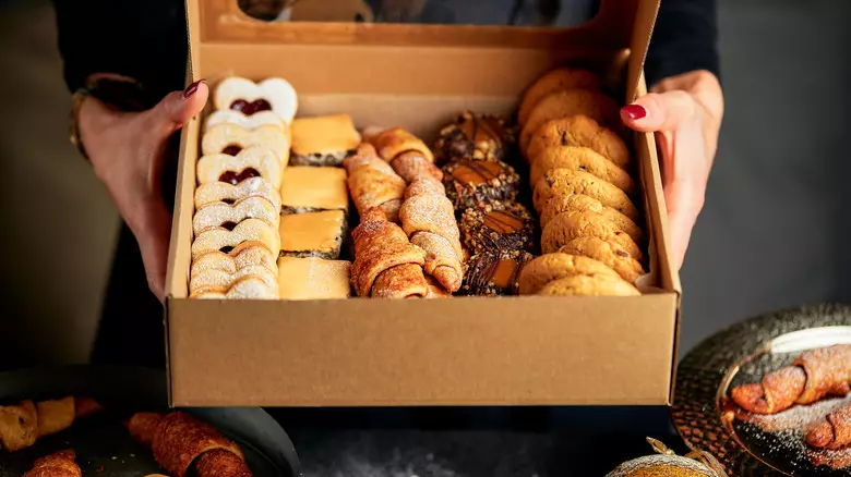 Fra Hänn déi Karton Bäckerei Këscht gefëllt mat verschiddenen Kichelcher fir Cookie Austausch Konzept ze illustréieren