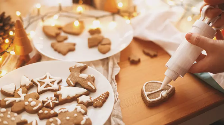 Plack vu wäisse Äis Gingerbread Cookien an Hänn mat enger Äispistoul fir en anert Cookie ze dekoréieren