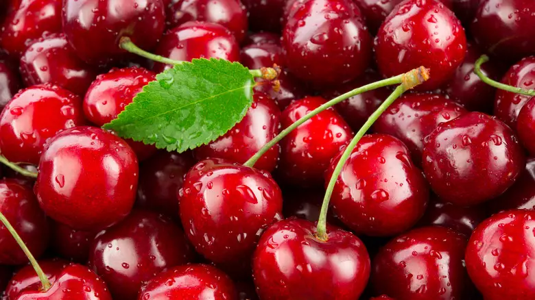 Okiti cherries, diẹ ninu awọn pẹlu stems, ọkan pẹlu kan bunkun.