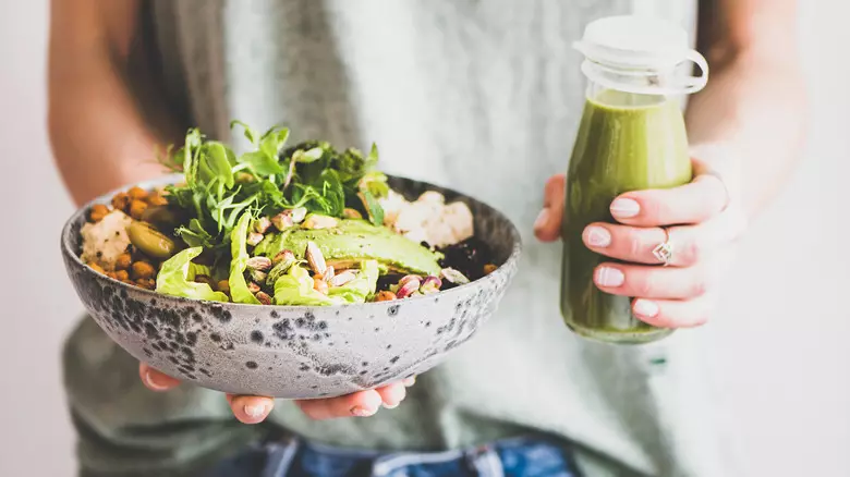 Orang yang memegang mangkuk salad dan smoothie hijau