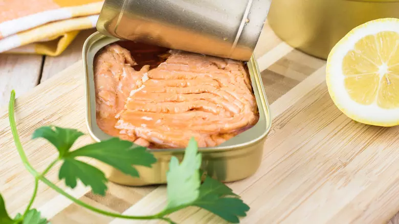 aperto lattina di salmone sul tagliere di legno