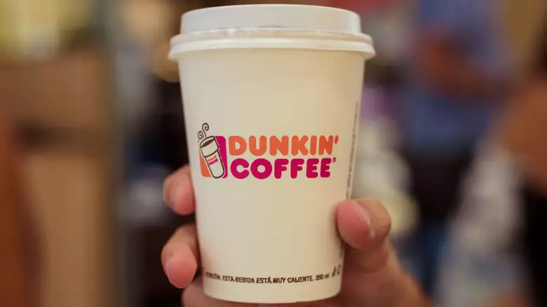 Orang yang memegang secangkir kopi Dunkin.