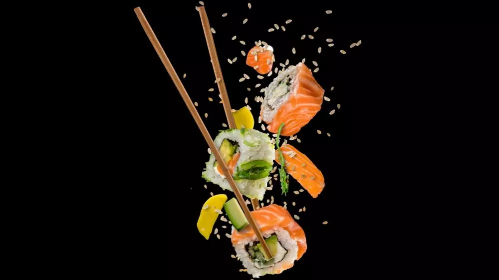 sushi a cikin iska tare da chopsticks da sesame tsaba