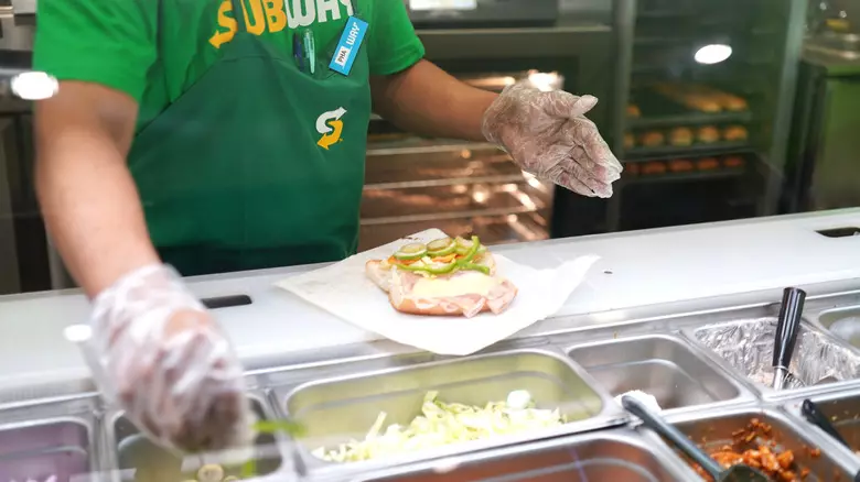 Artista do sanduíche do metrô montando uma refeição