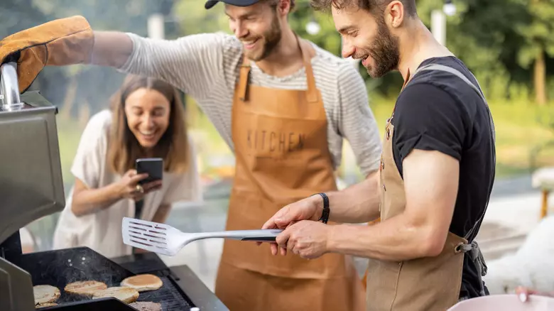 Fólk hlæjandi fyrir framan opið grill