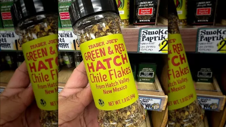 אדם מחזיק בקבוק של Green & Red Hatch Chile Flakes מ-Trader Joe's