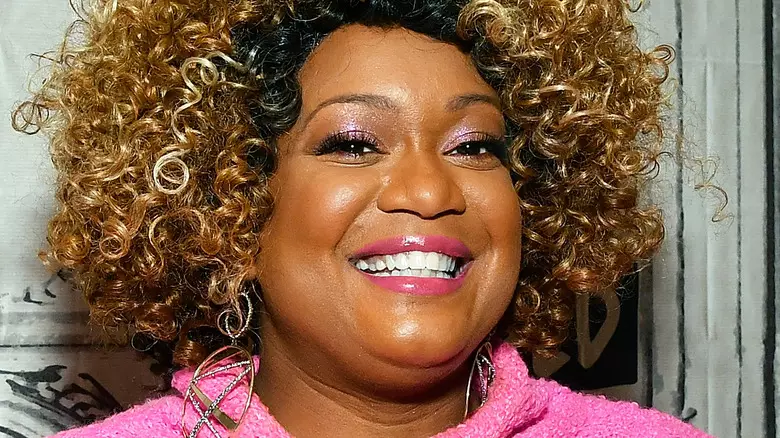 Sunny Anderson sonríe con una camisa rosa