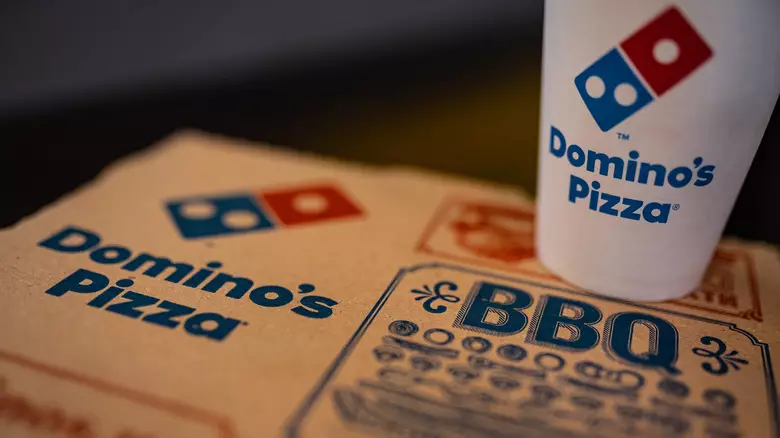 Pudełko na pizzę i biały kubek Domino