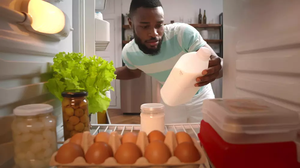 lalaki na kumukuha ng gatas mula sa refrigerator